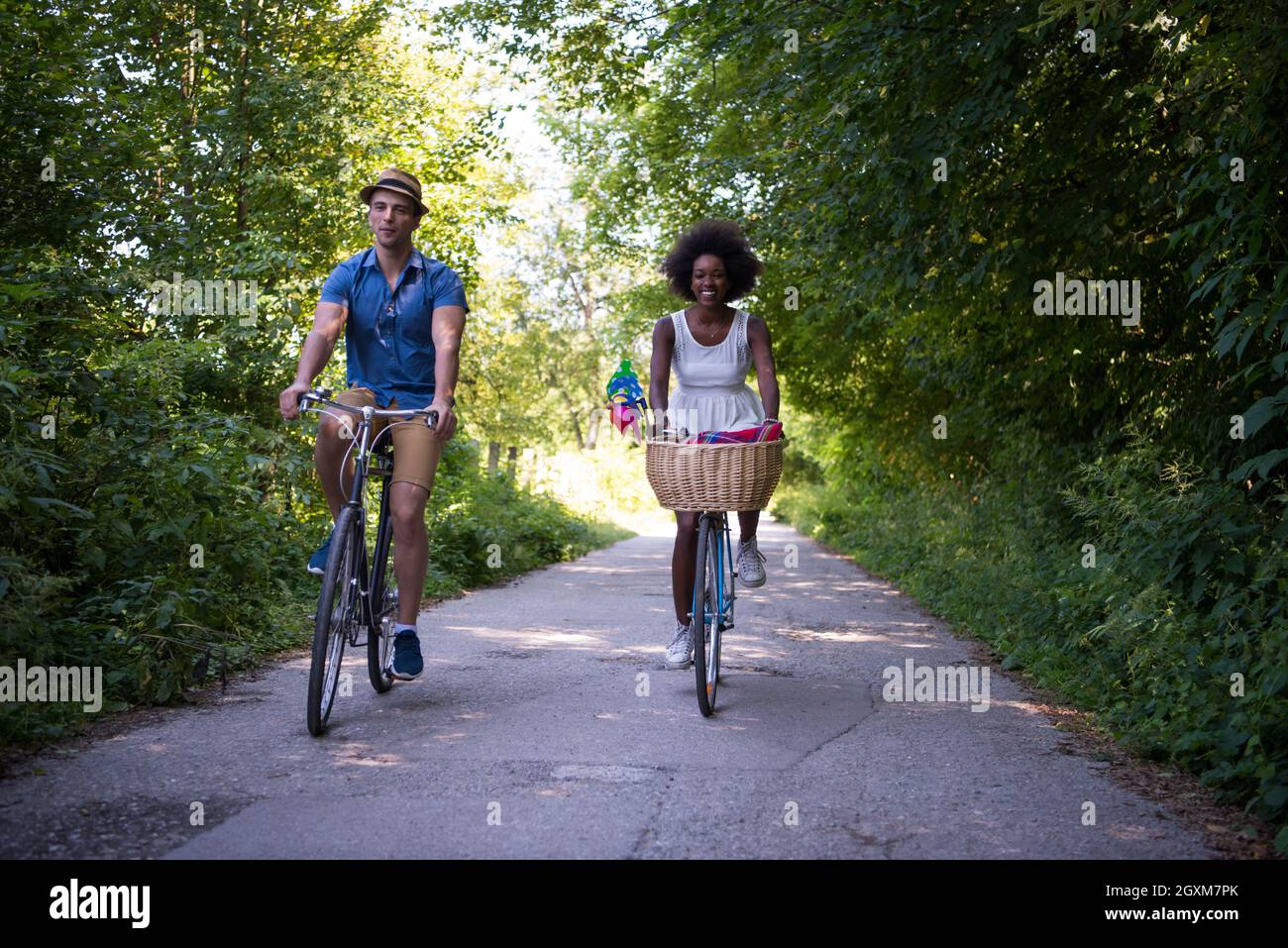 a young man and a beautiful African American girl enjoying a bike ride in nature on a sunny ...