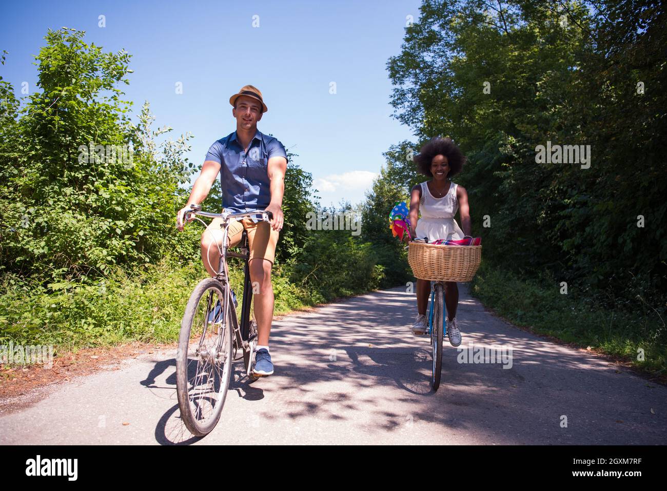 a young man and a beautiful African American girl enjoying a bike ride in nature on a sunny ...
