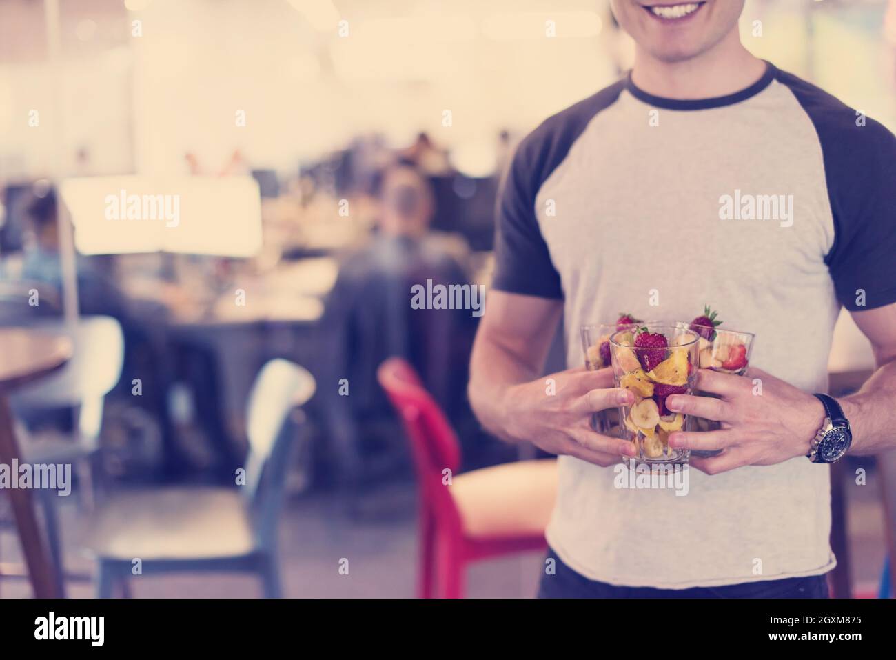 closeup of a young software developer eating a fruit salad from a clear ...