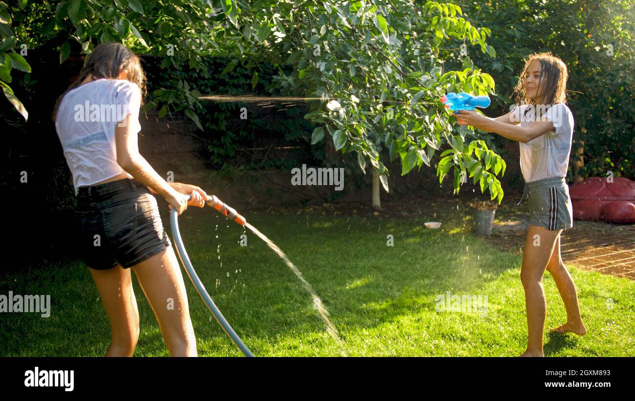 Two happy laughing girls splashing water and playing with water guns ...