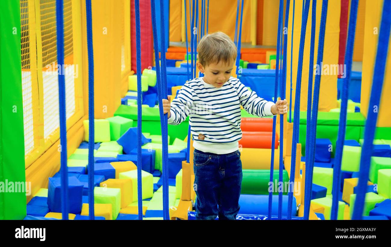 Little concentrated boy balancing on ropes and bridges in children ...