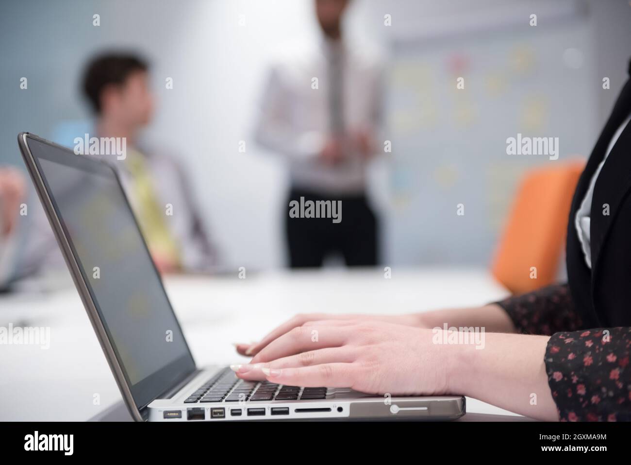 young business woman on meeting usineg laptop computer, blured group of ...