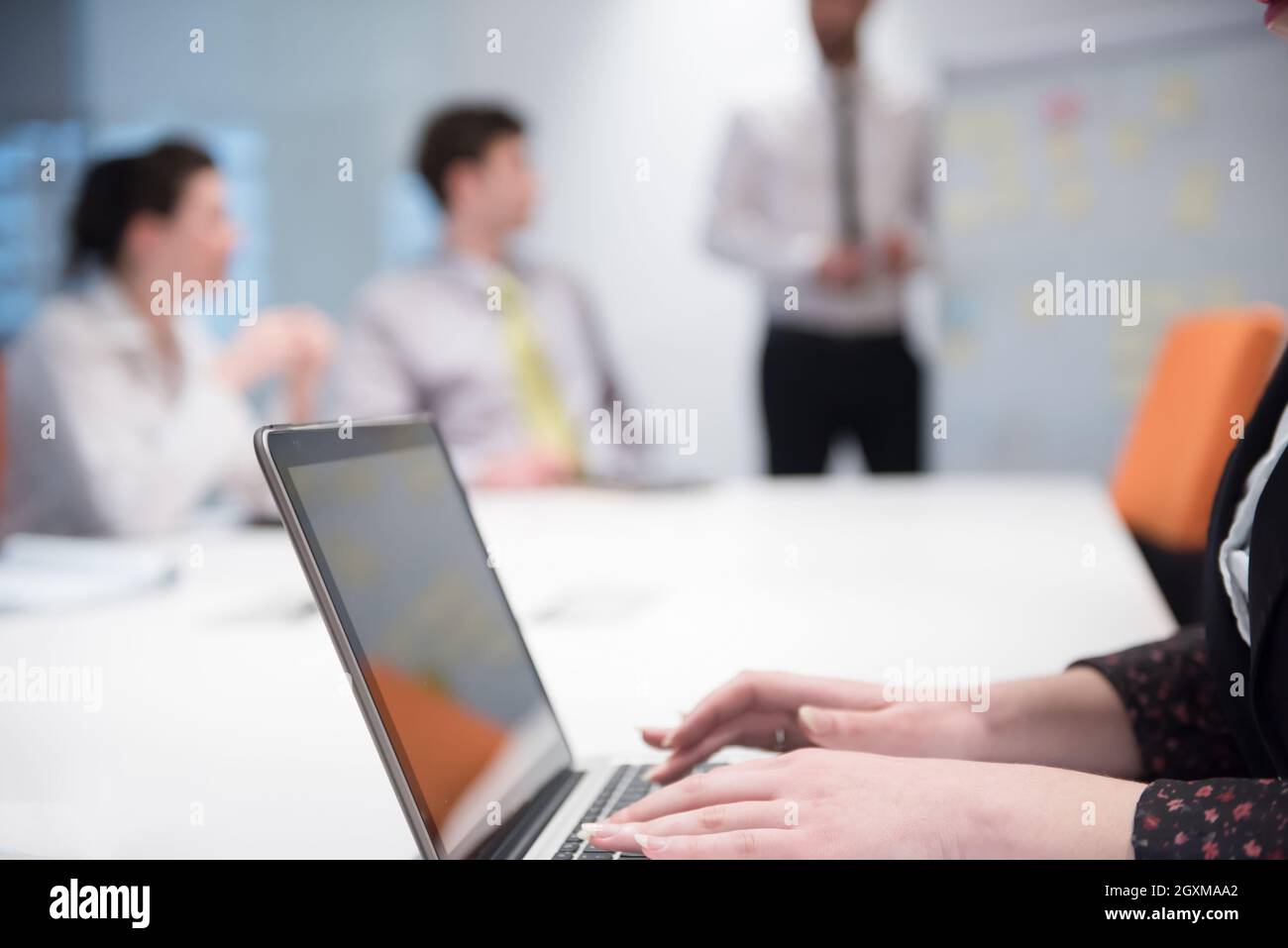 young business woman on meeting usineg laptop computer, blured group of ...