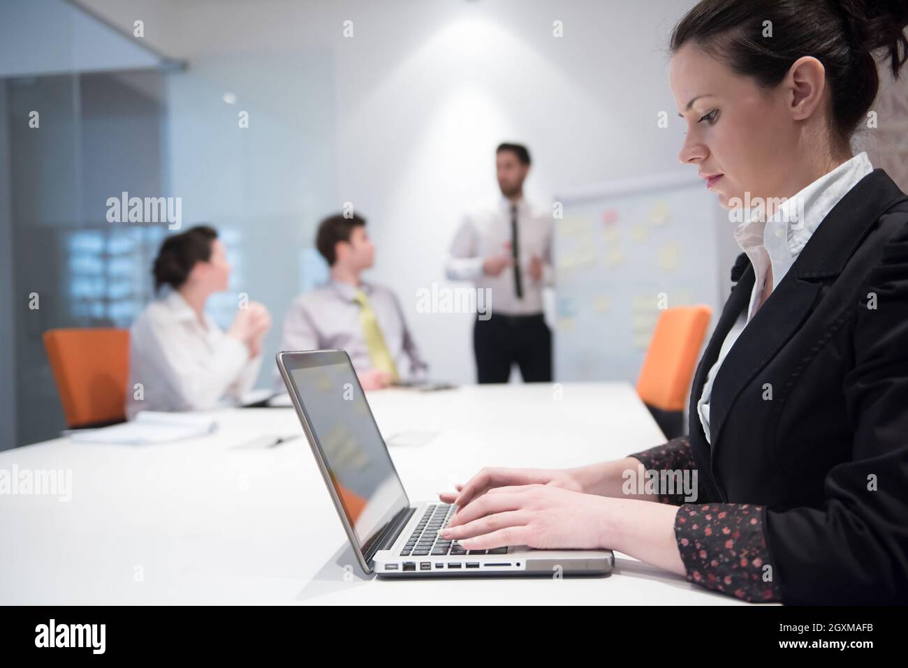young business woman on meeting usineg laptop computer, blured group of ...