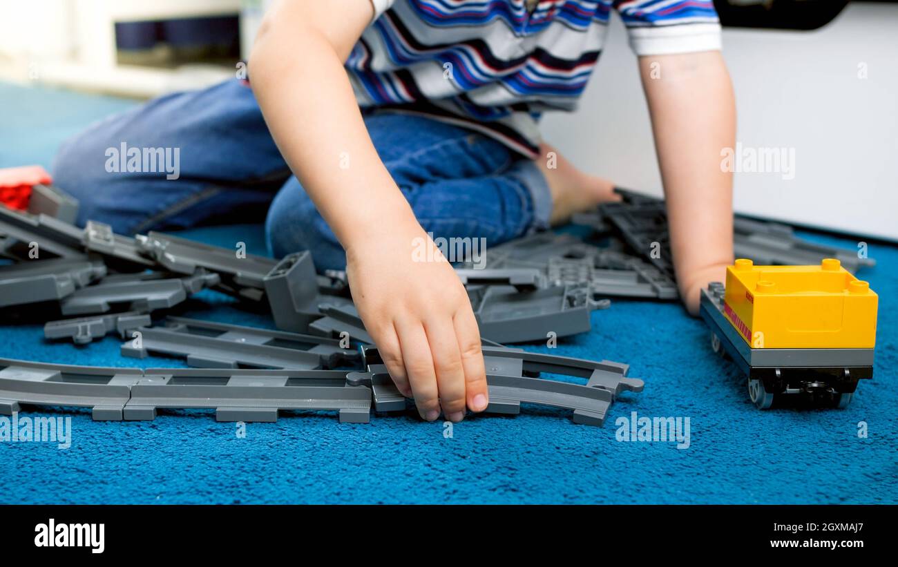 Closeup image of child's hand assembling toy railroad on floor Stock ...