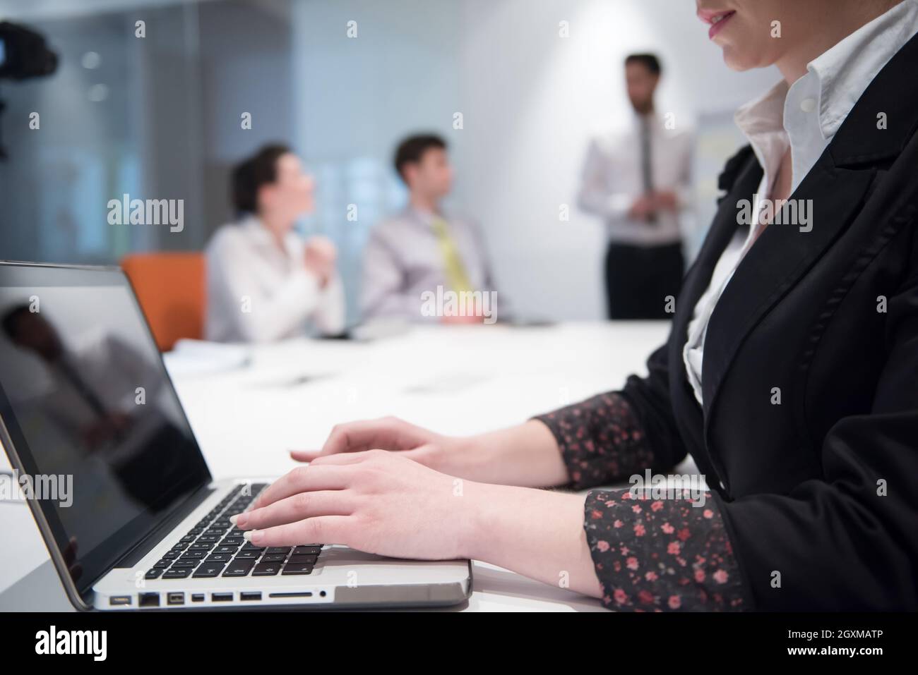 young business woman on meeting usineg laptop computer, blured group of ...