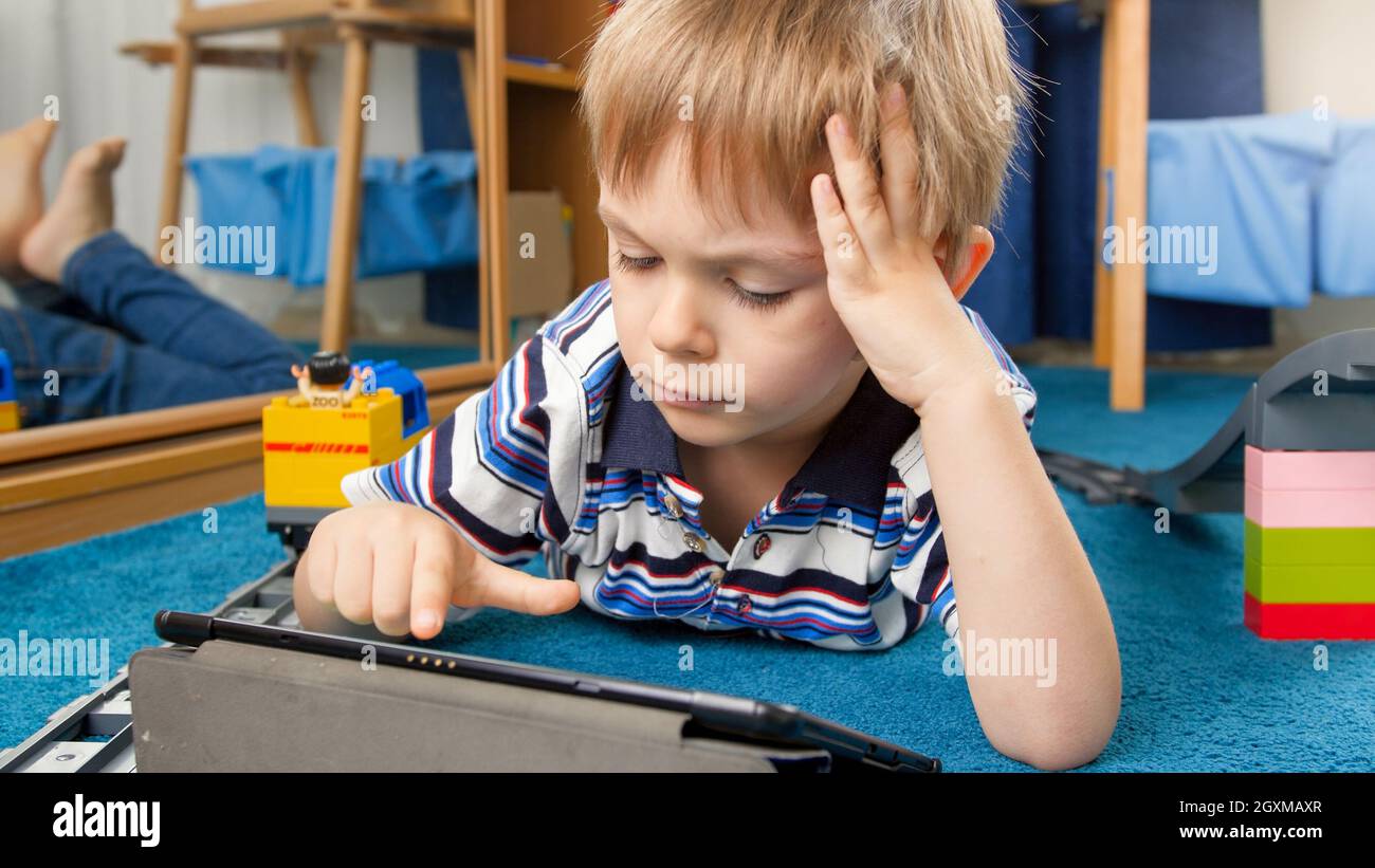 Portrait of concentrated little boy using tablet computer Stock Photo ...