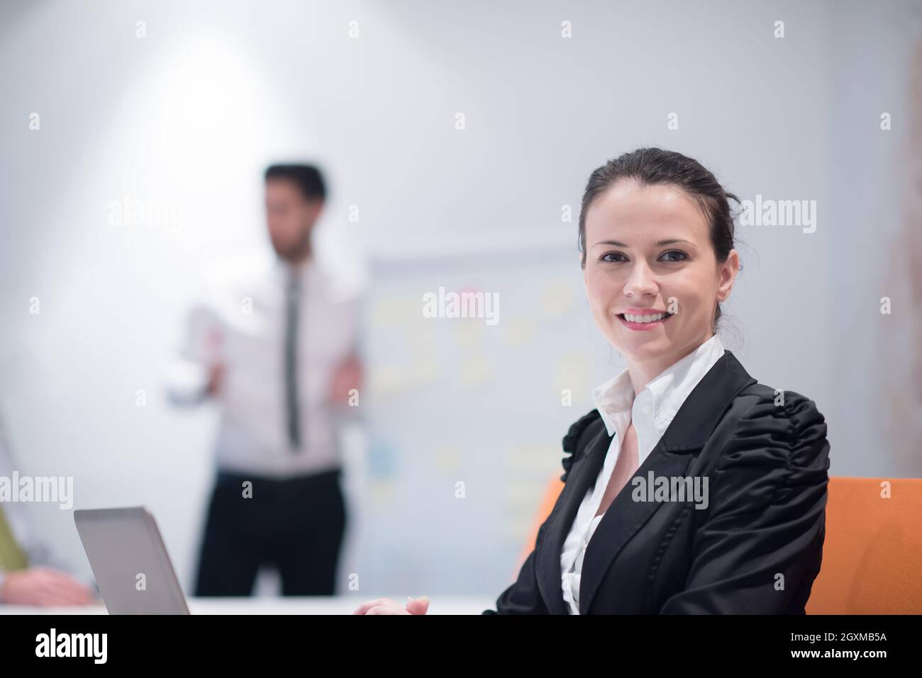young business woman on meeting usineg laptop computer, blured group of ...