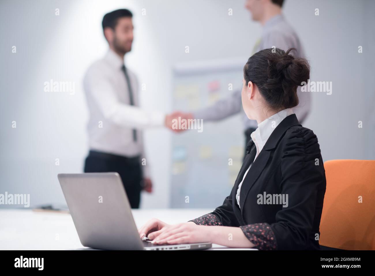 young business woman on meeting usineg laptop computer, blured group of ...