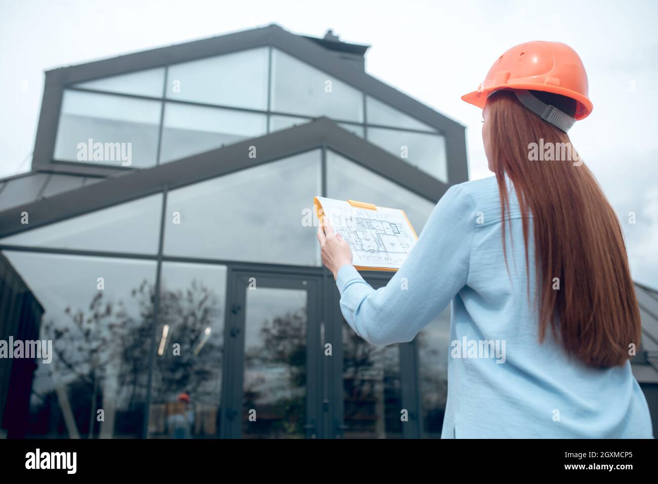 Woman looking at construction plan and building Stock Photo - Alamy