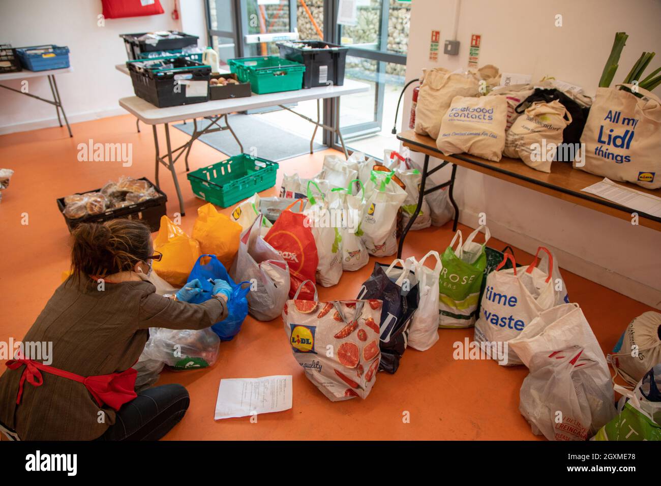 A woman volunteer at a food bank sorting bags of donated food in ...