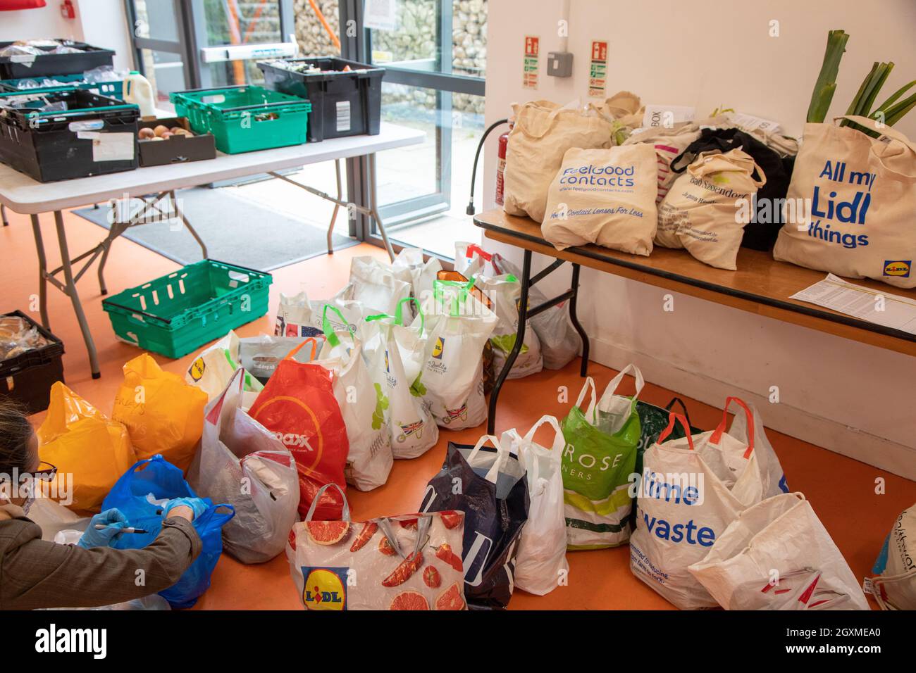 A woman volunteer at a food bank sorting bags of donated food in ...