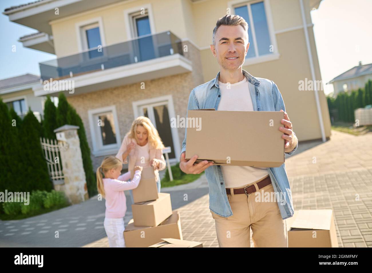 Man with box wife with daughter behind Stock Photo - Alamy