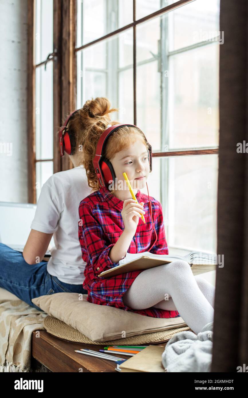 Two sisters study at home. The girl writes in a notebook. Children in ...