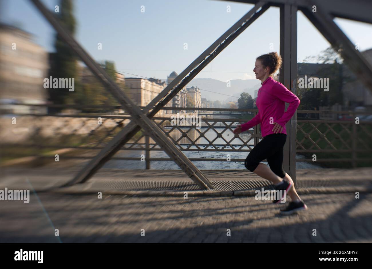 sporty woman running on sidewalk at early morning jogging with city ...
