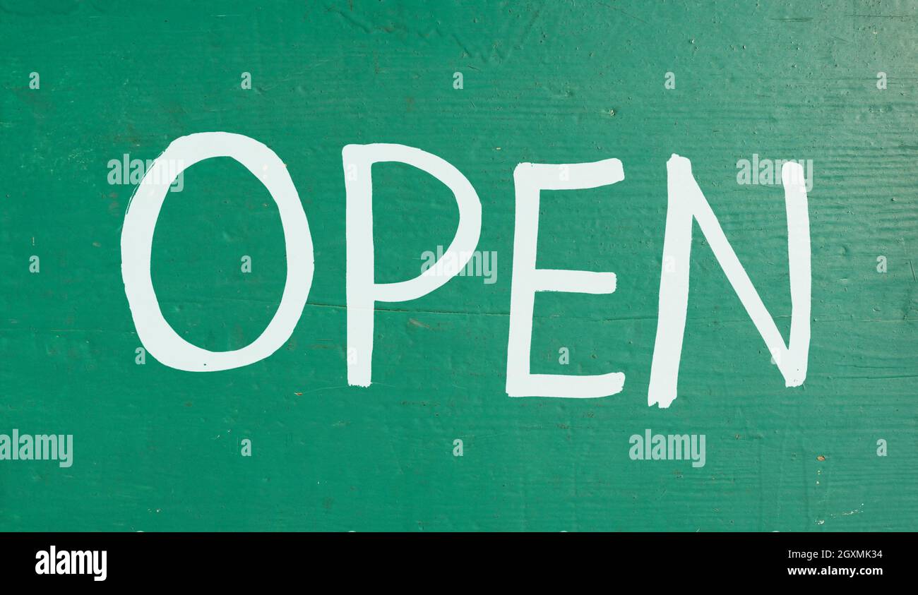 Handwritten open sign label tag on a store front, white paint on green ...