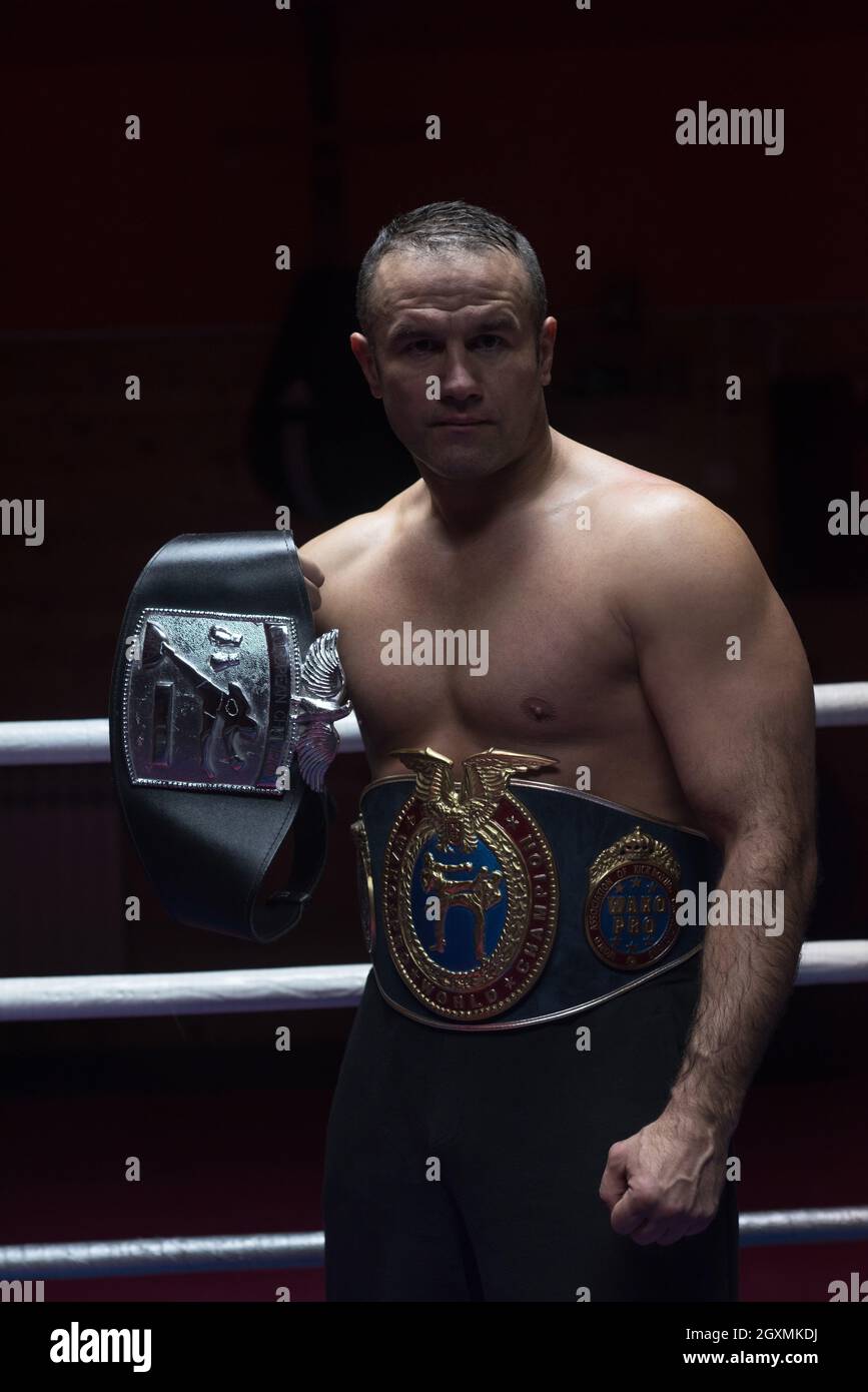portrait of muscular professional kick boxer with his championship belt ...