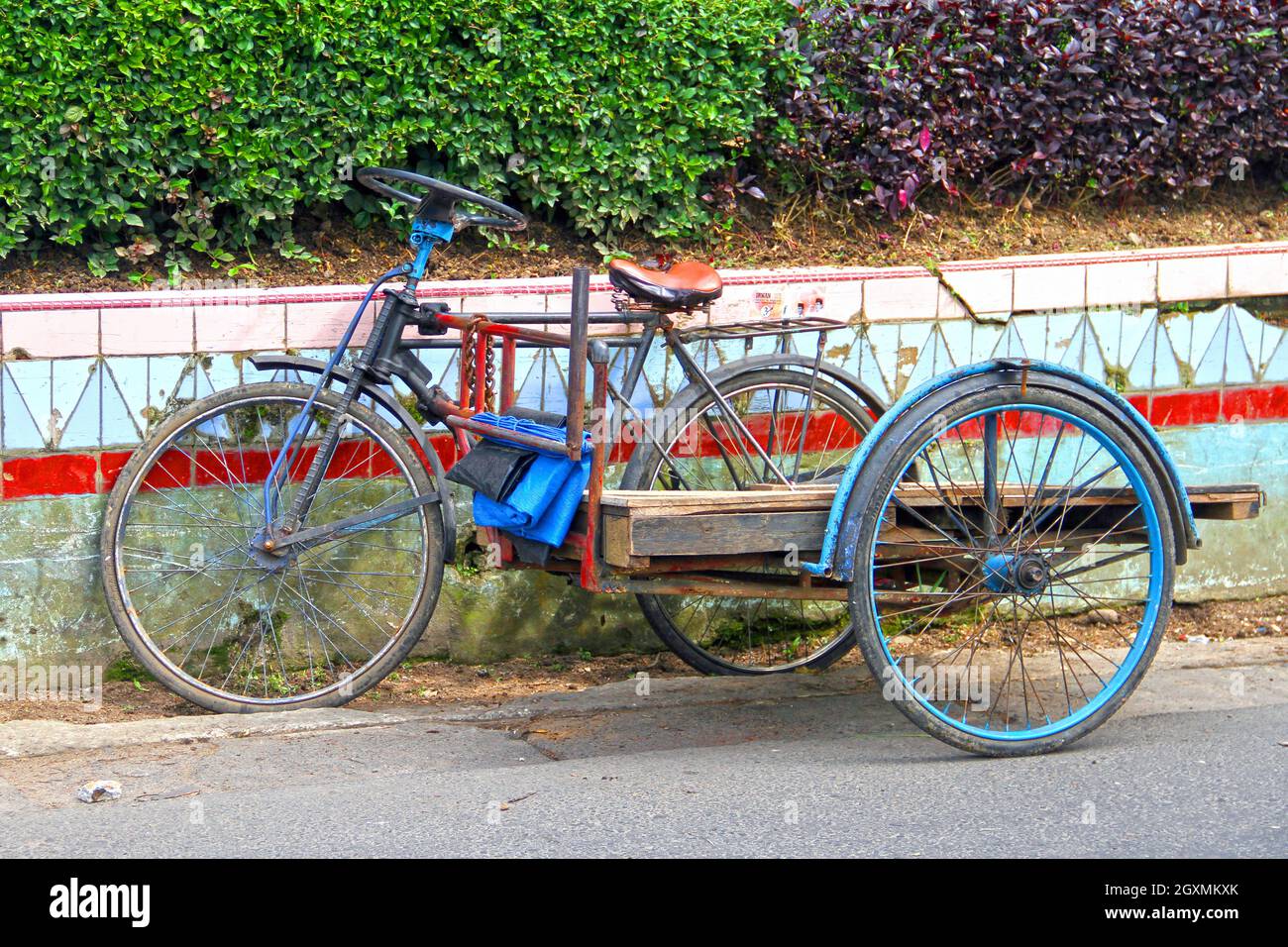 A antique style tricycle parked at the side of a road used for ...