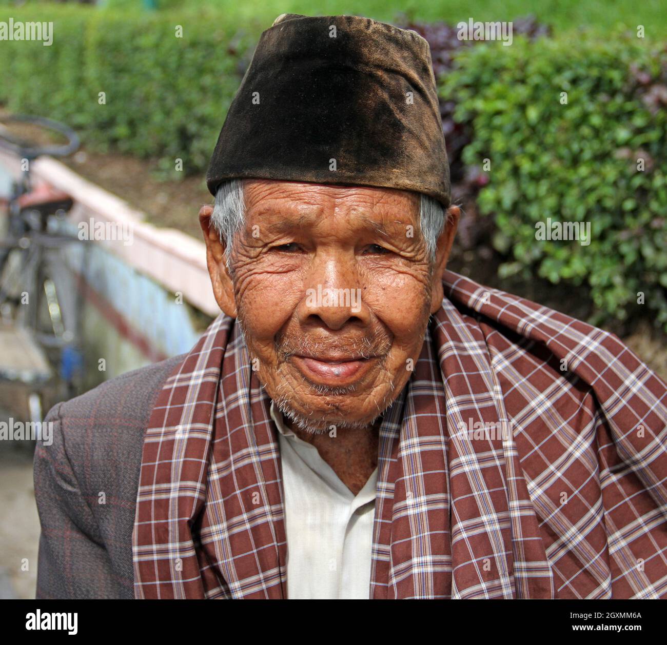 An elderly man on the street wearing a peci religious hat, smiling ...