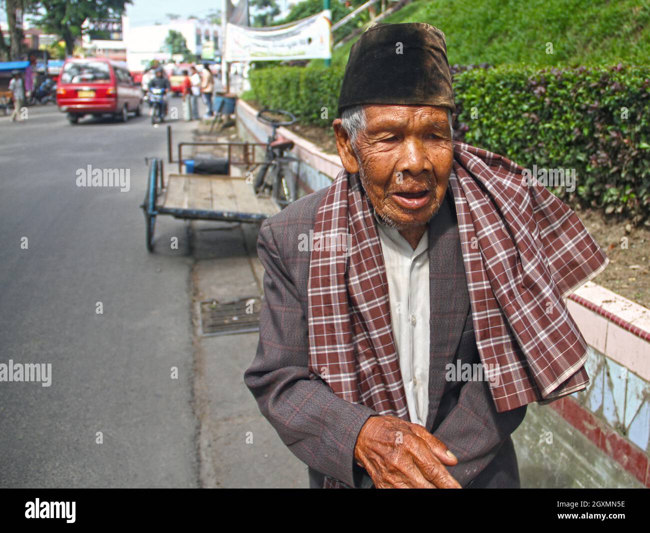 An elderly man on the street wearing a songkok Moslem hat with a sarong ...