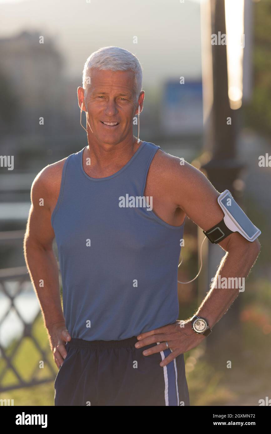 portrait of handsome senior jogging man while relaxing and take break ...