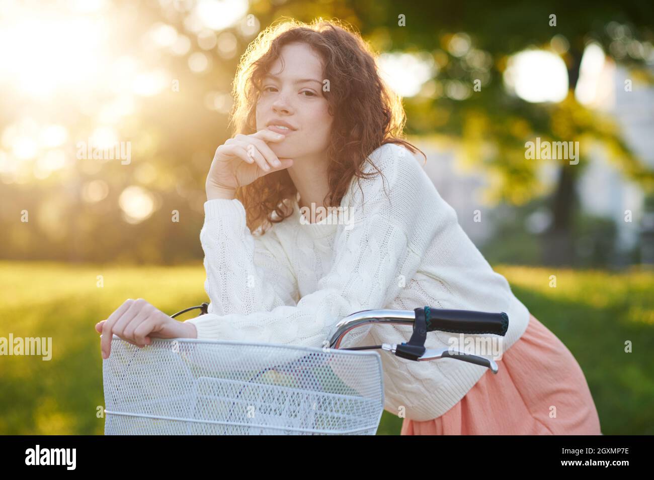 Cute young girl on a bike in the park looking thoughtful Stock Photo - Alamy