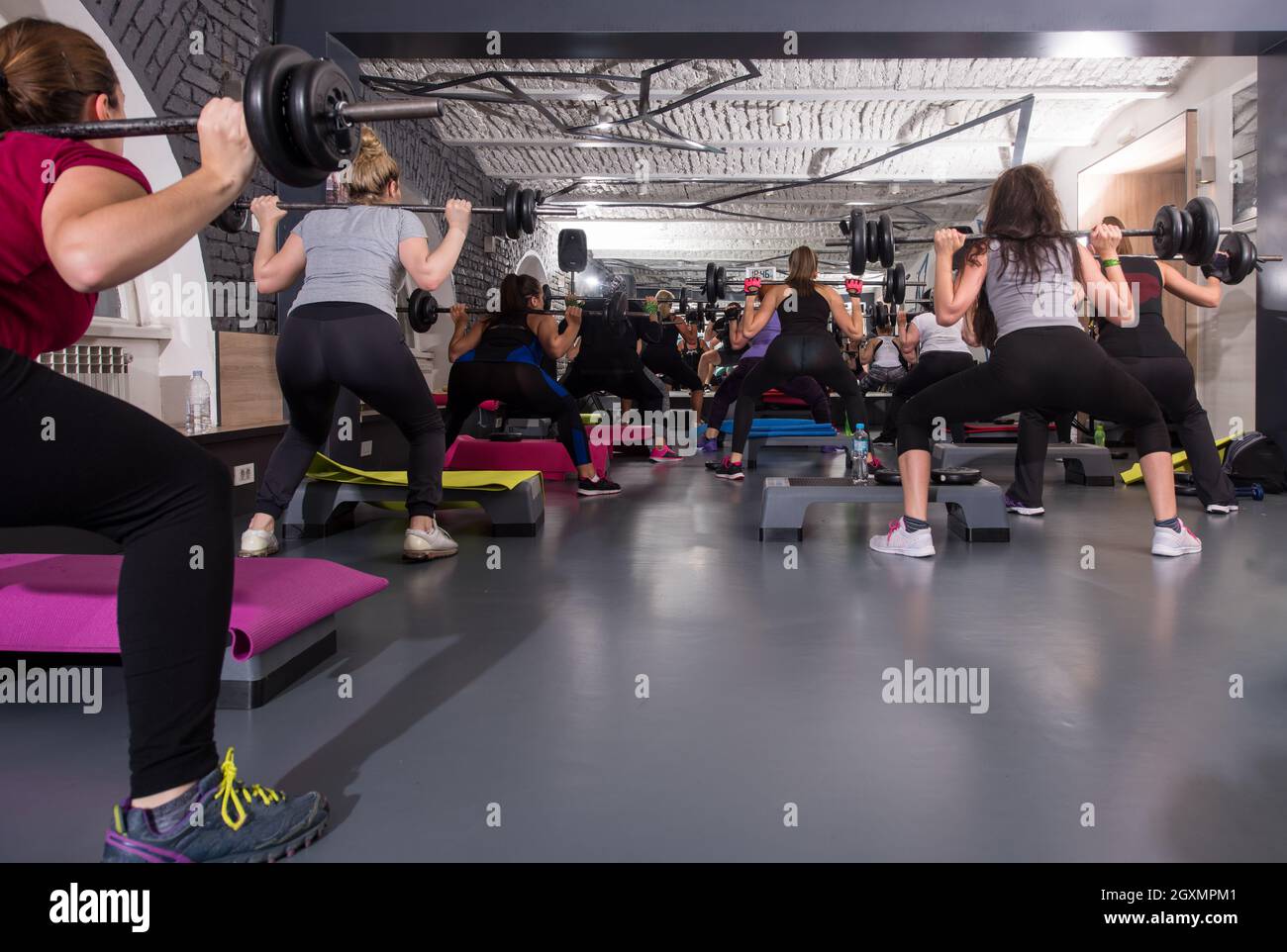 group of young healthy sporty women working out with instructor using ...