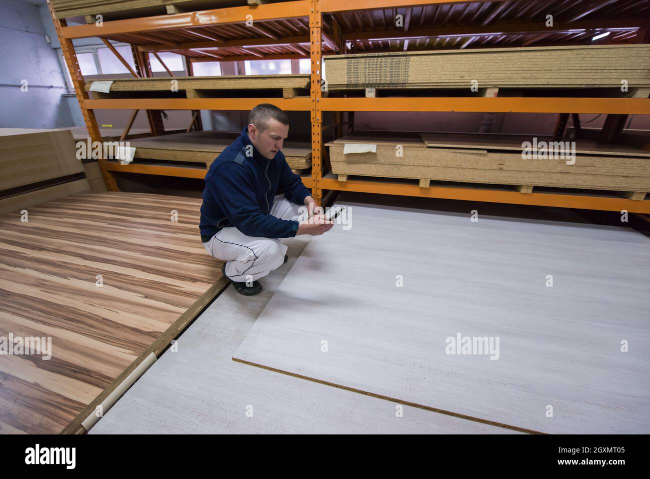 young man carpenter using a mobile phone to calculate measures for ...