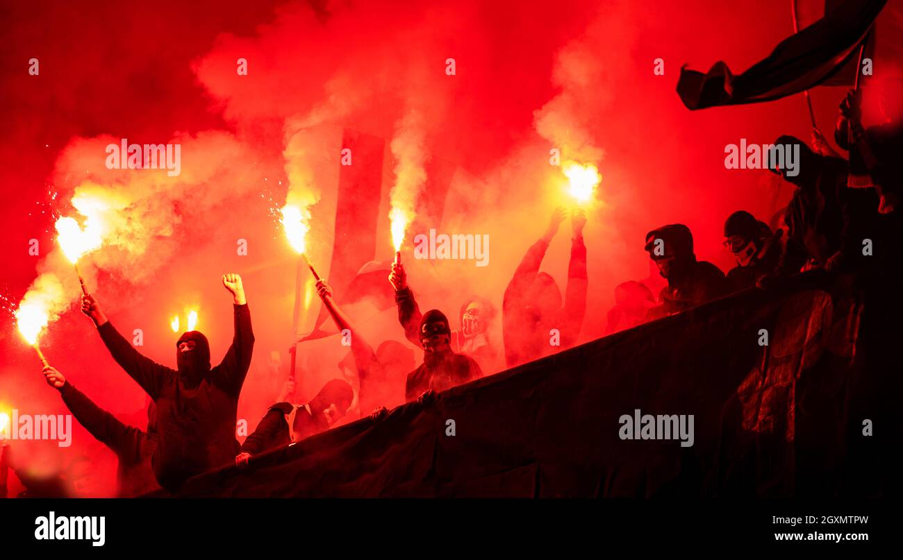 football hooligans with mask holding torches in fire while supporting ...