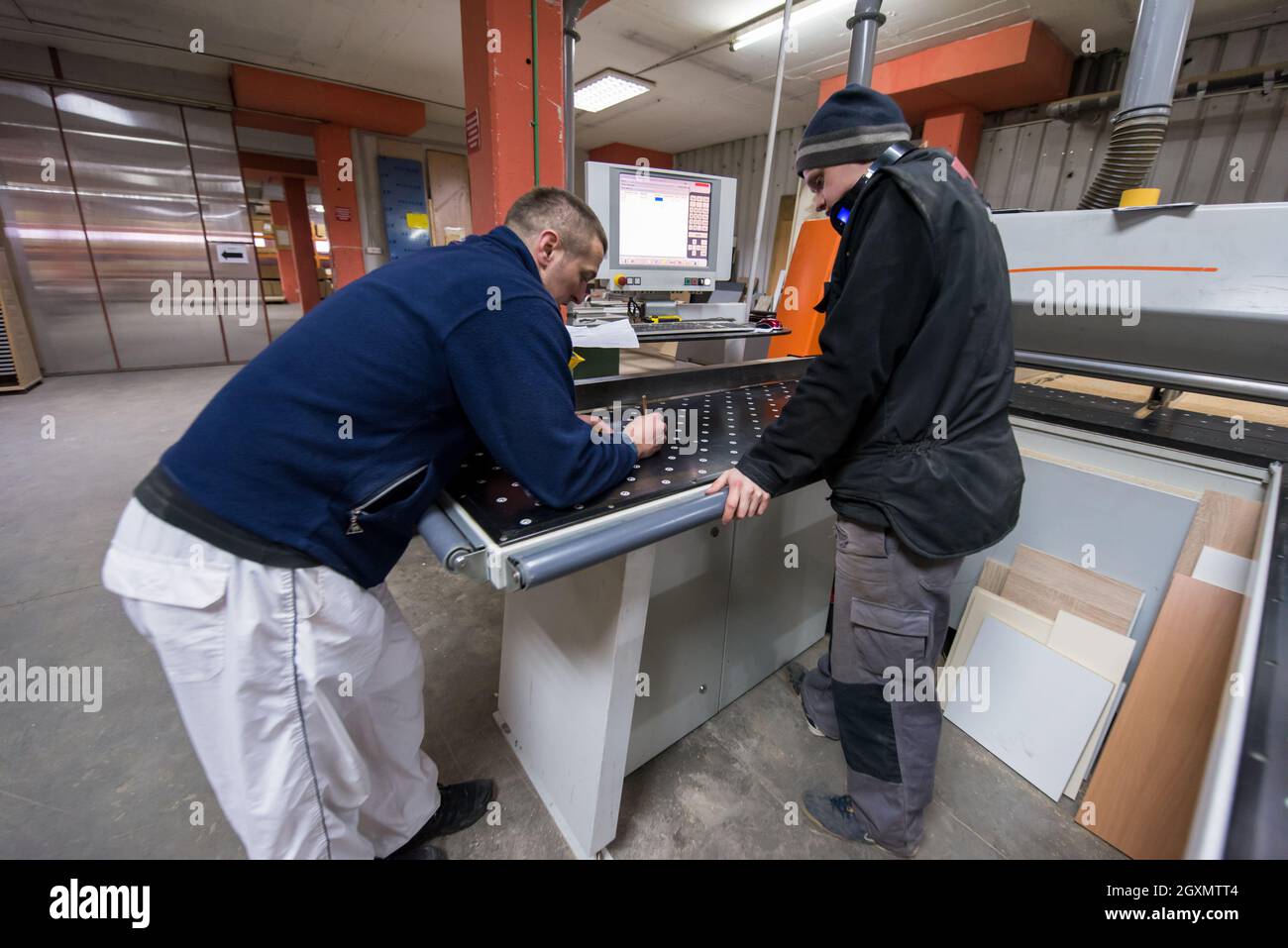 two young carpenters calculating and programming a cnc wood working ...