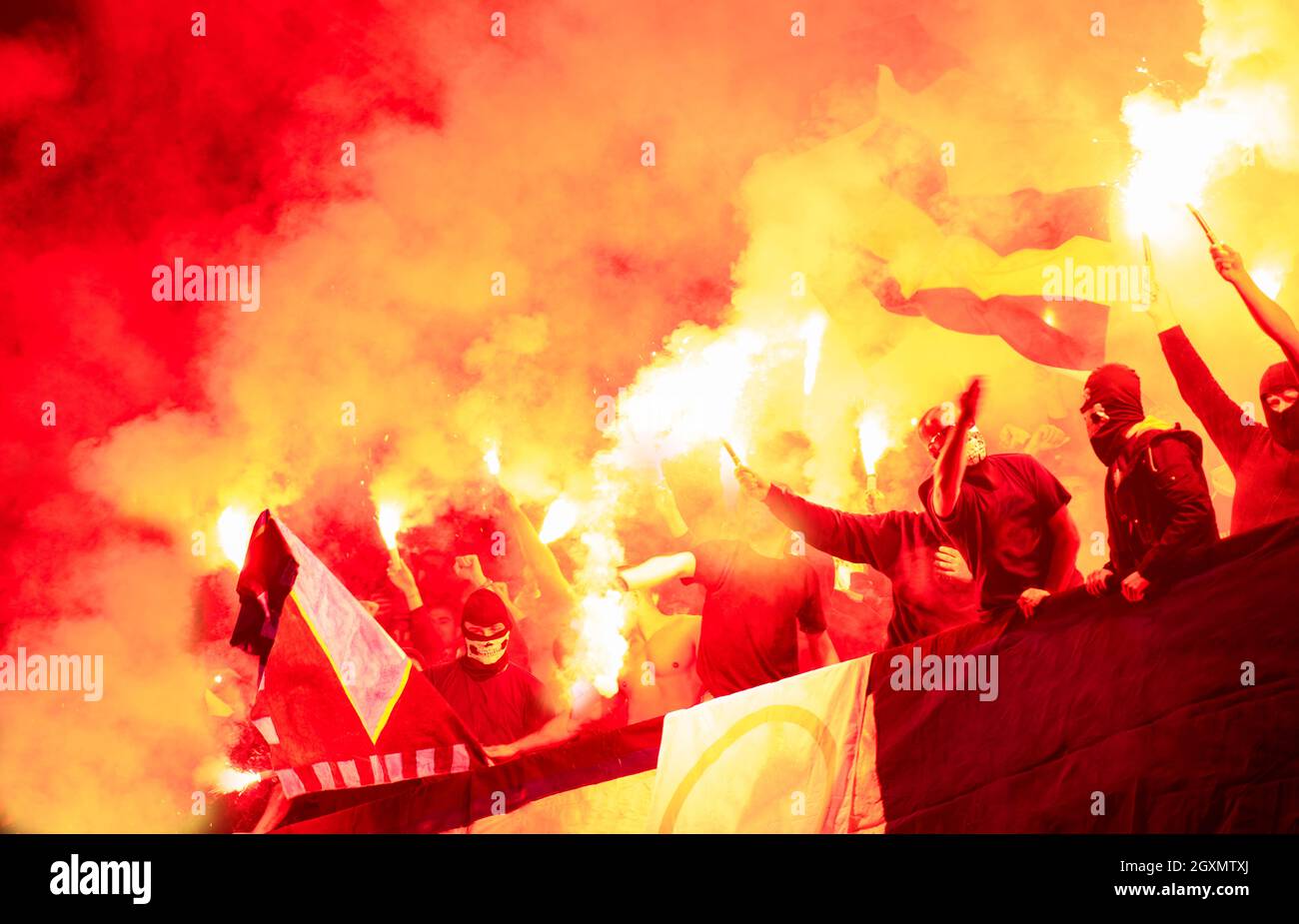 football hooligans with mask holding torches in fire while supporting ...