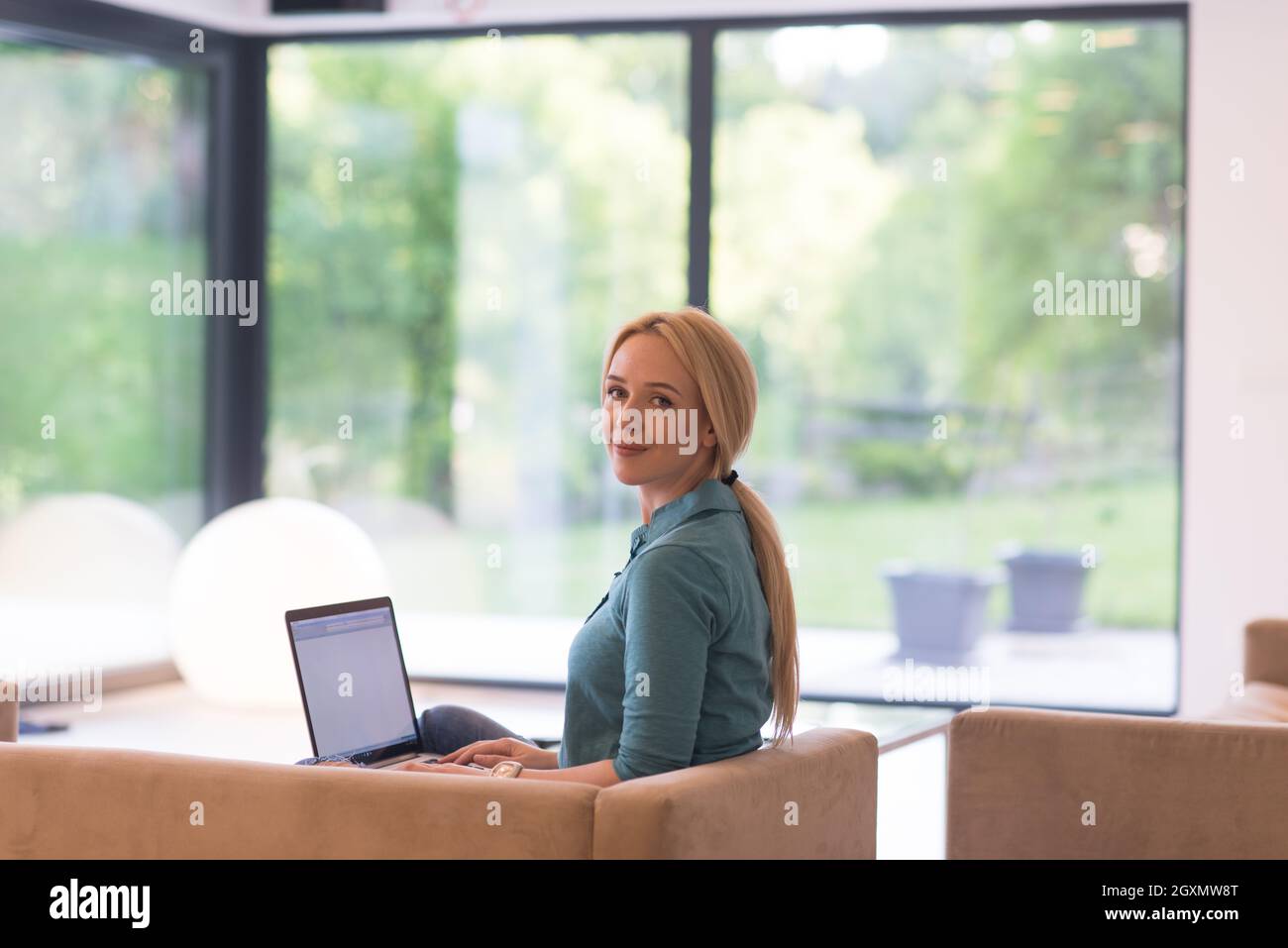 Young woman using her laptop computer in her luxury modern home ...