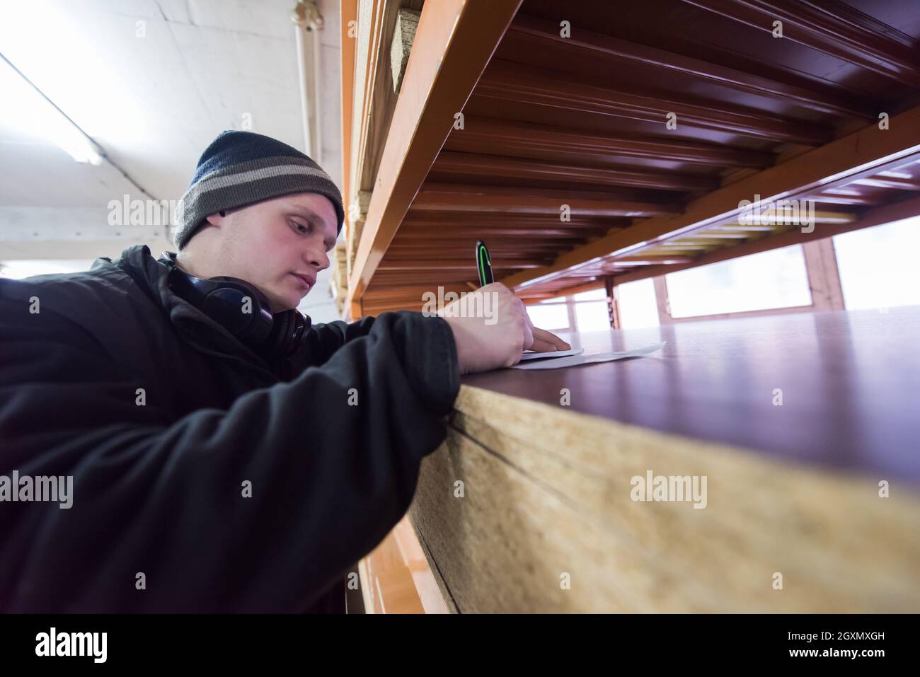 young man carpenter using pen while writing a receipt in big modern ...