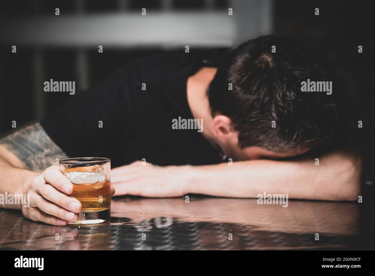 drunk man sleeping at a bar table with a glass of whiskey in hand Stock ...