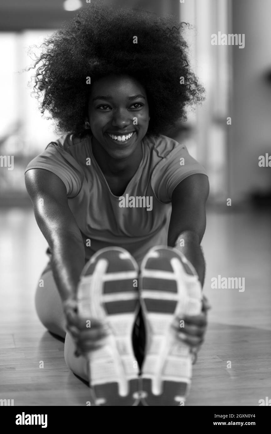 happy young african american woman in a gym stretching and warming up ...