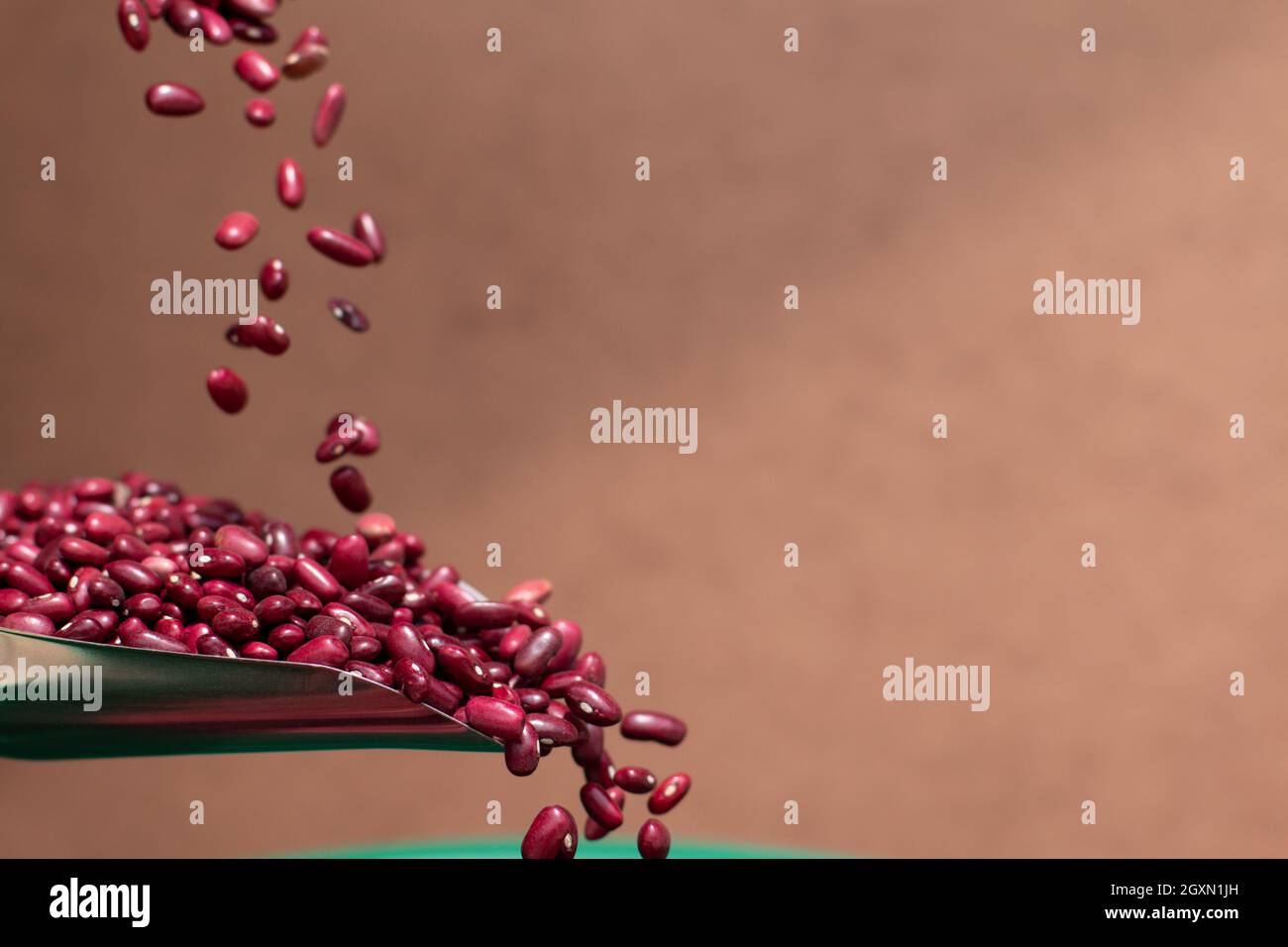 Isolated beans falling on a spoon on brown background Stock Photo - Alamy