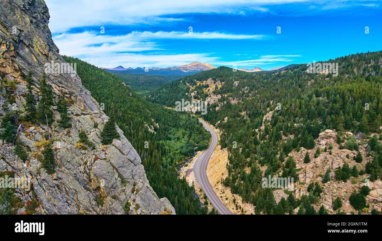 Cliff mountain of rocks next to highway road travelling through pine ...