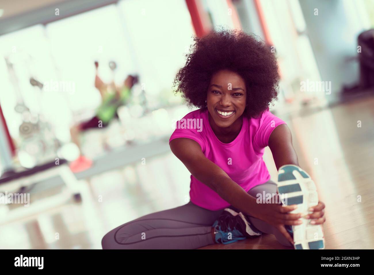 happy young african american woman in a gym stretching and warming up ...