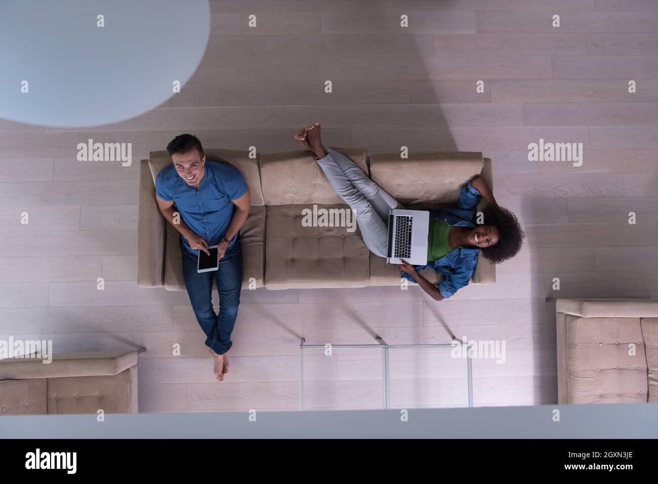 Young multiethnic couple relaxes in the luxury living room, using a ...