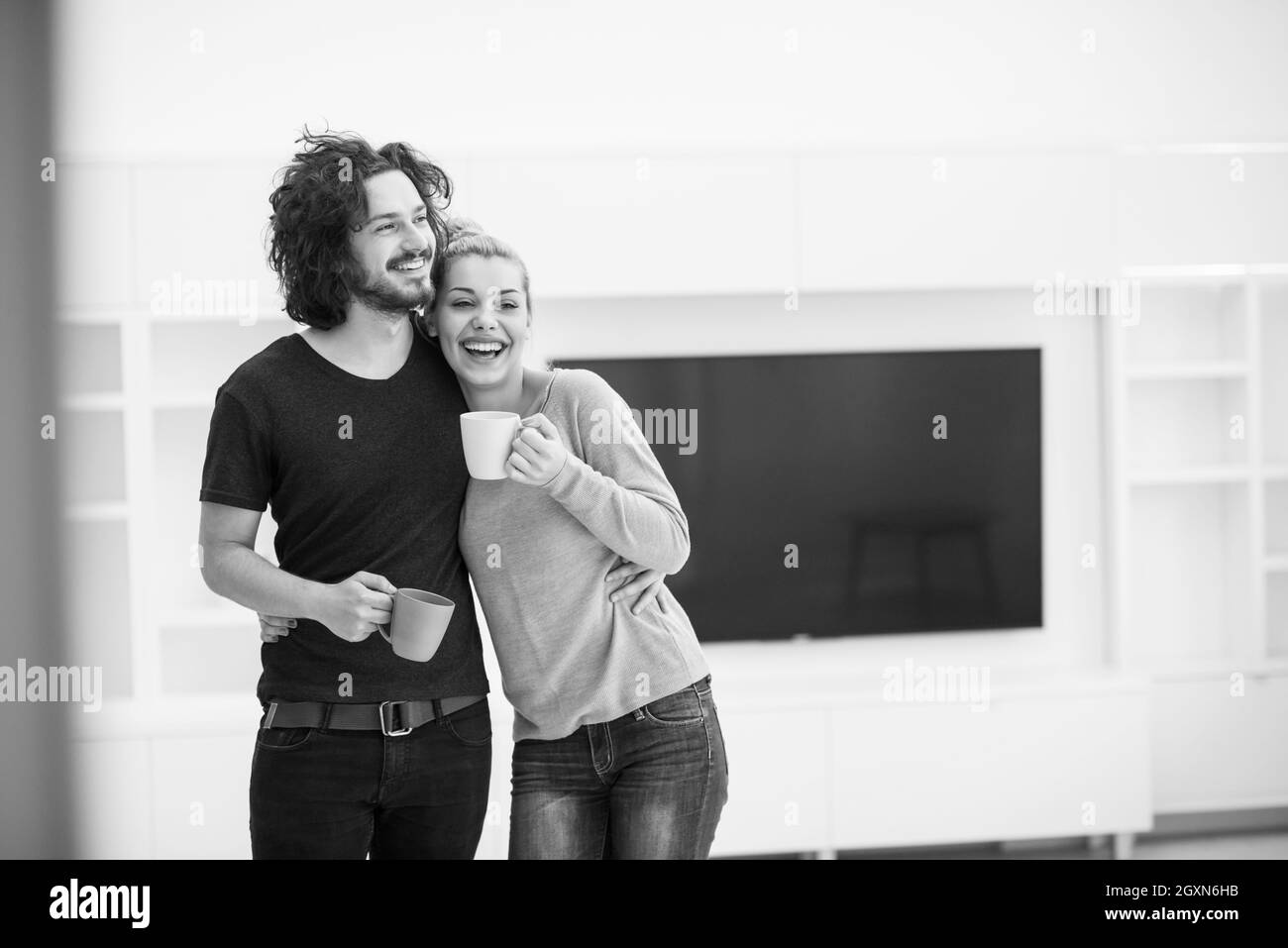 Portrait of a happy young beautiful couple hugging and drinking coffee ...
