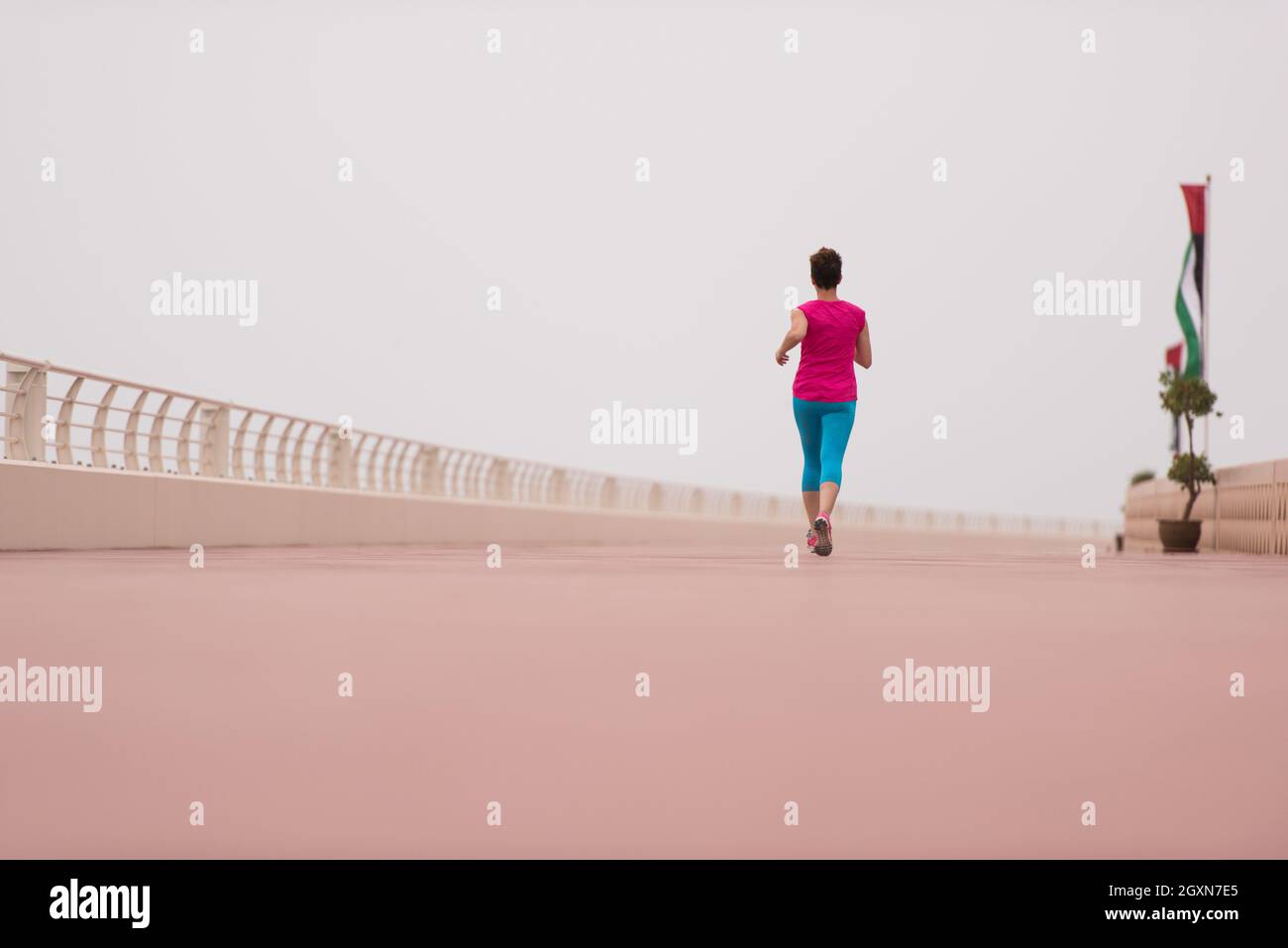 very active young beautiful woman busy running on the promenade along ...