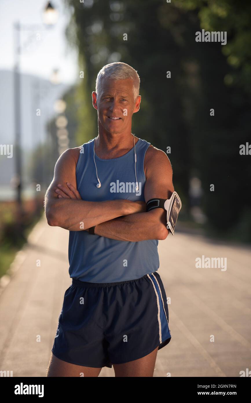portrait of handsome senior jogging man while relaxing and take break ...