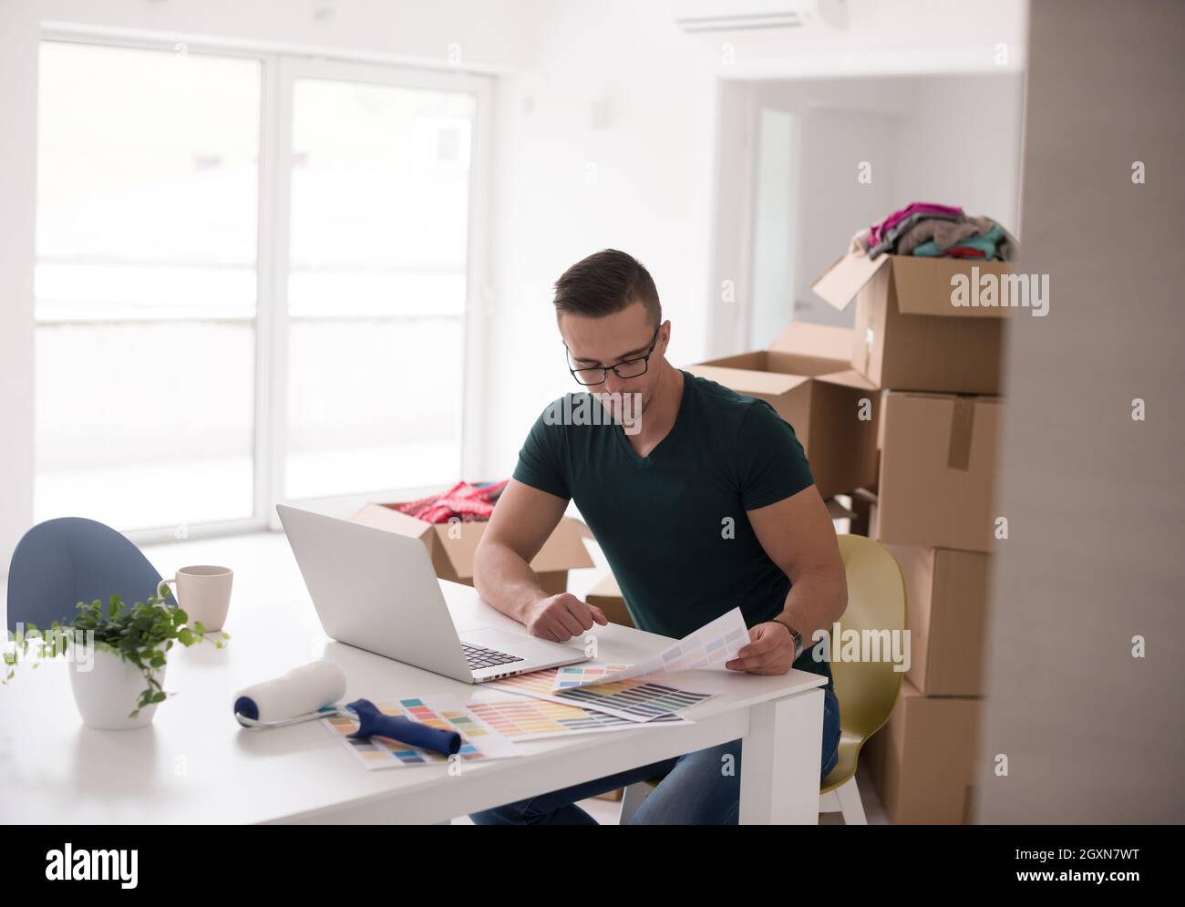 Young man moving in a new home. Man at the table using notebook laptop ...