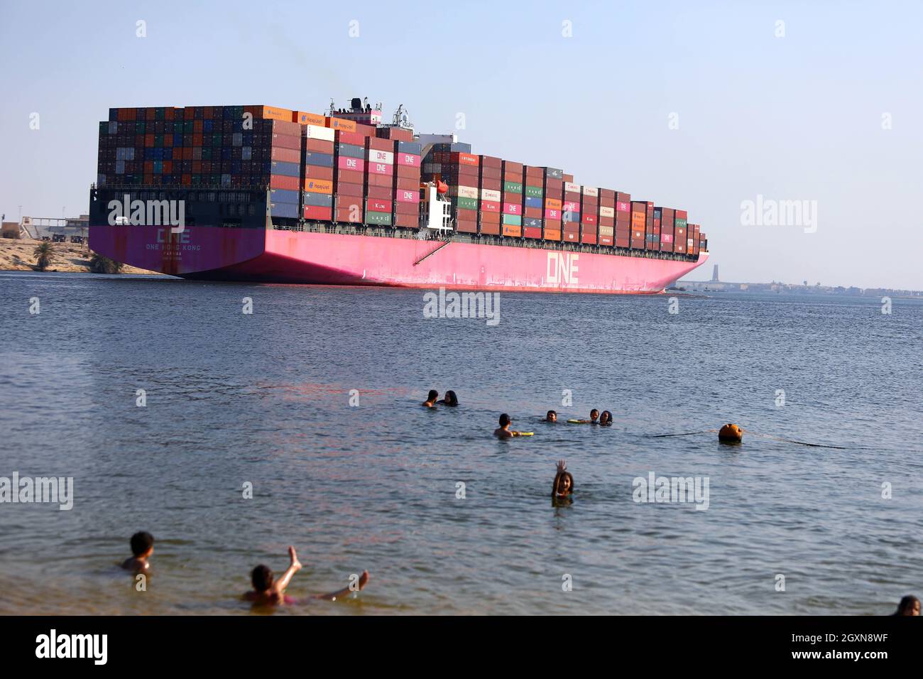 Ismailia, Egypt. 5th Oct, 2021. People play in the water as a ship ...