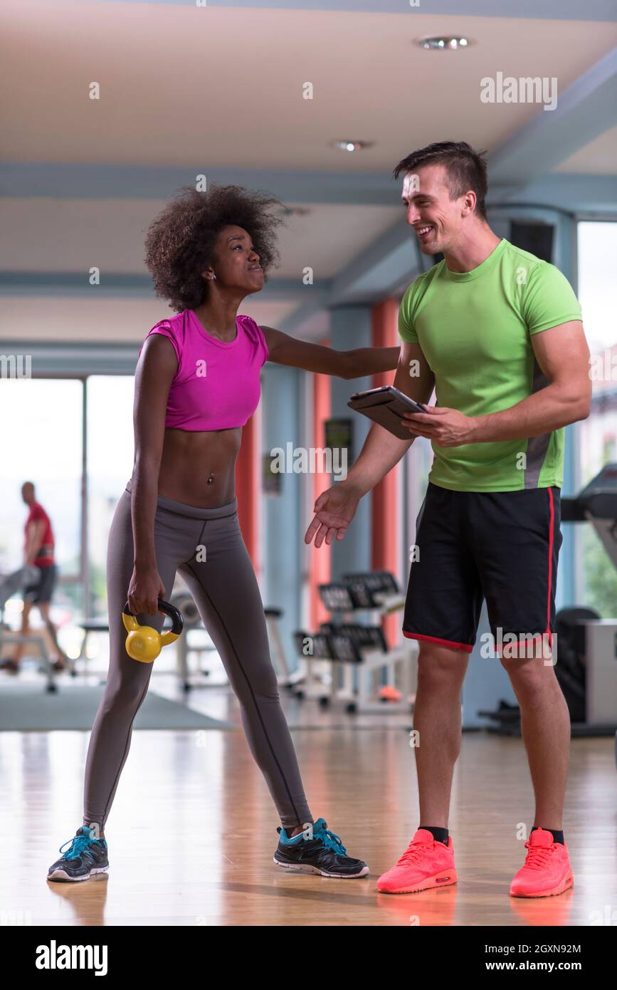 healthy young couple in crossfit gym weights workout with personal ...