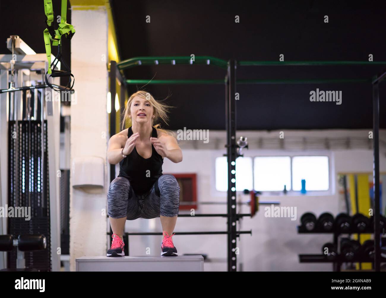 young athletic woman training jumping on fit box at cross fitness gym ...