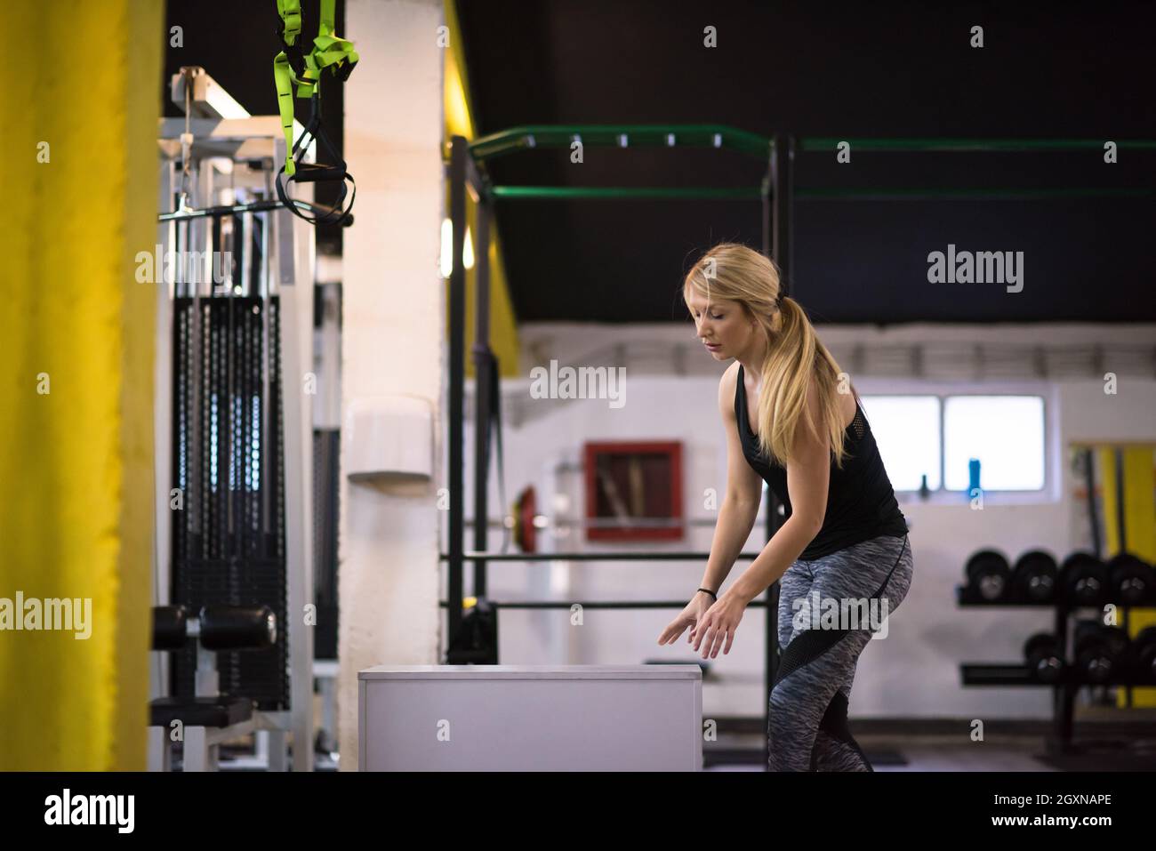 young athletic woman training jumping on fit box at cross fitness gym ...