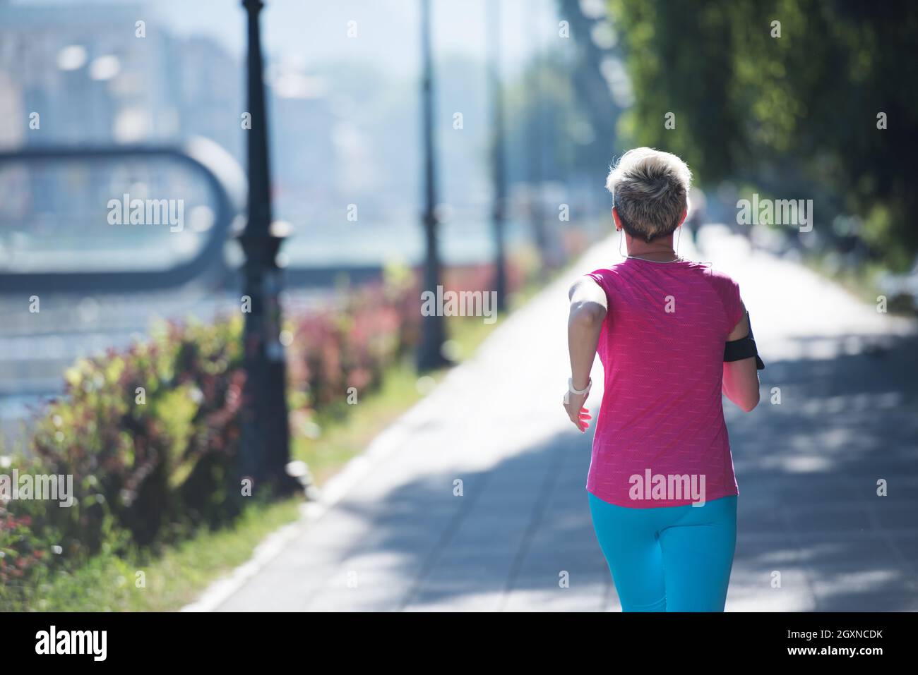 sporty woman running on sidewalk at early morning with city sunrise ...