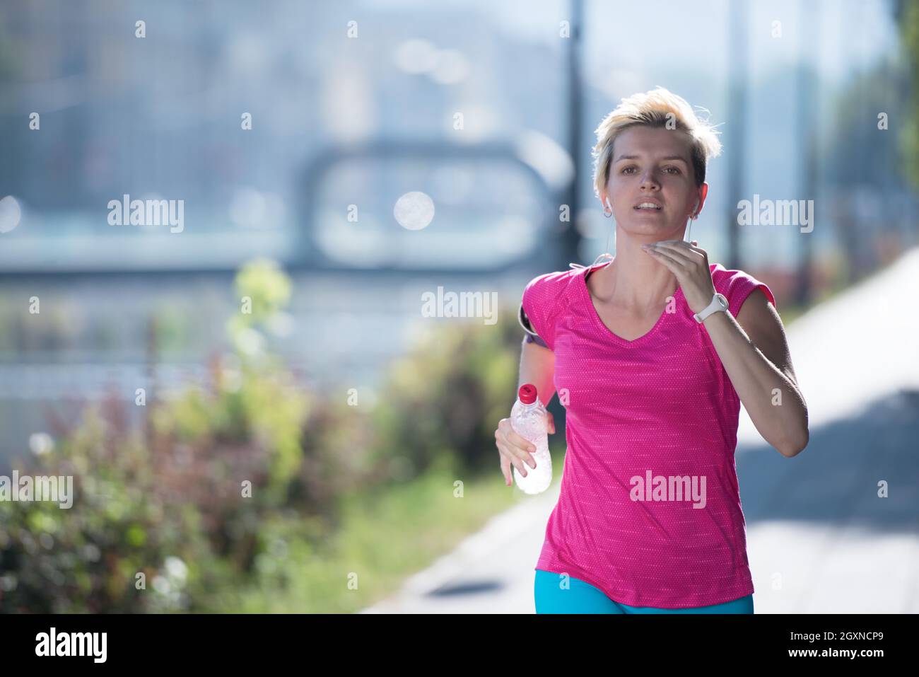 sporty woman running on sidewalk at early morning with city sunrise ...