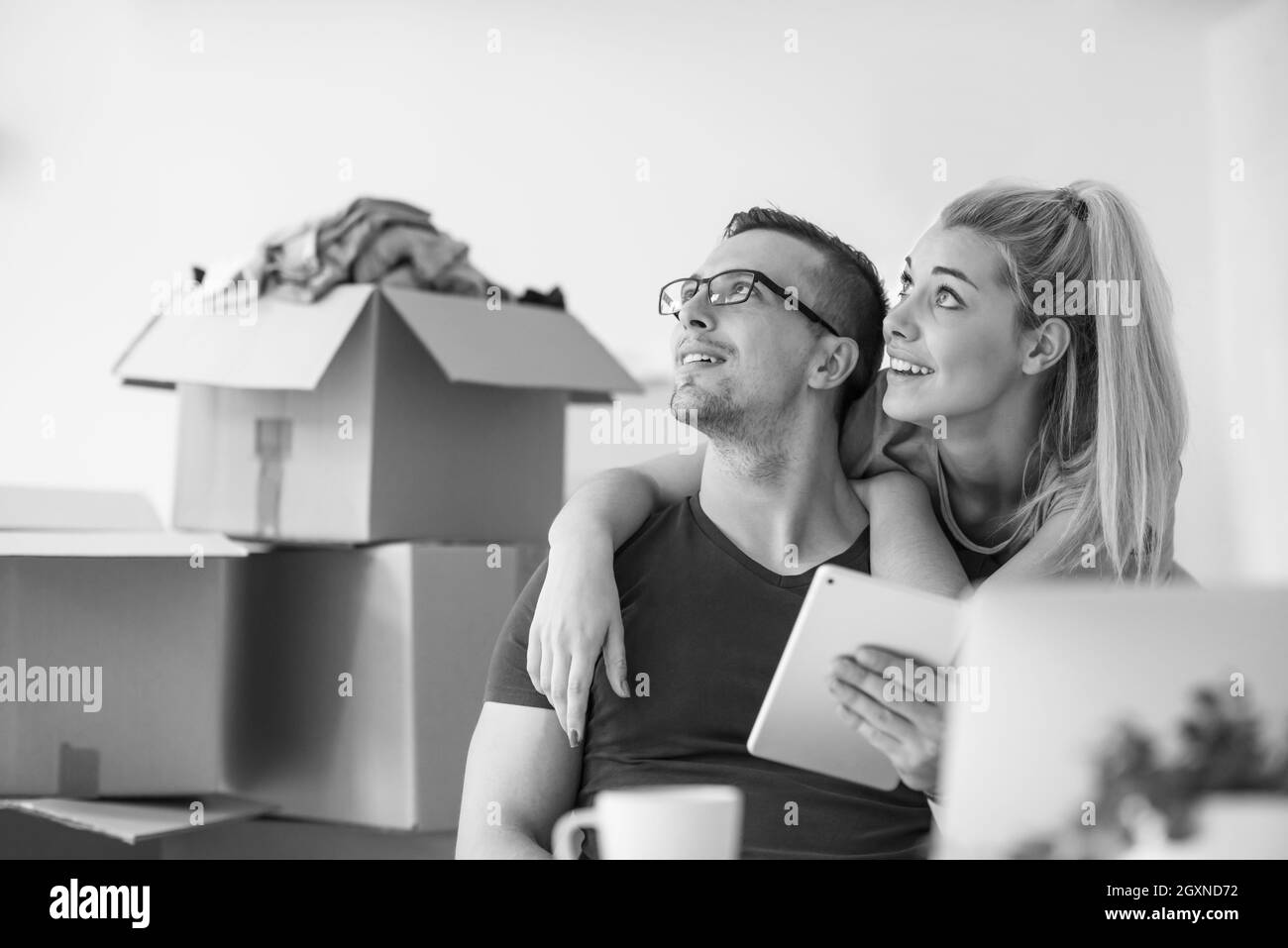 Young couple moving in a new home. Man and woman at the table using ...